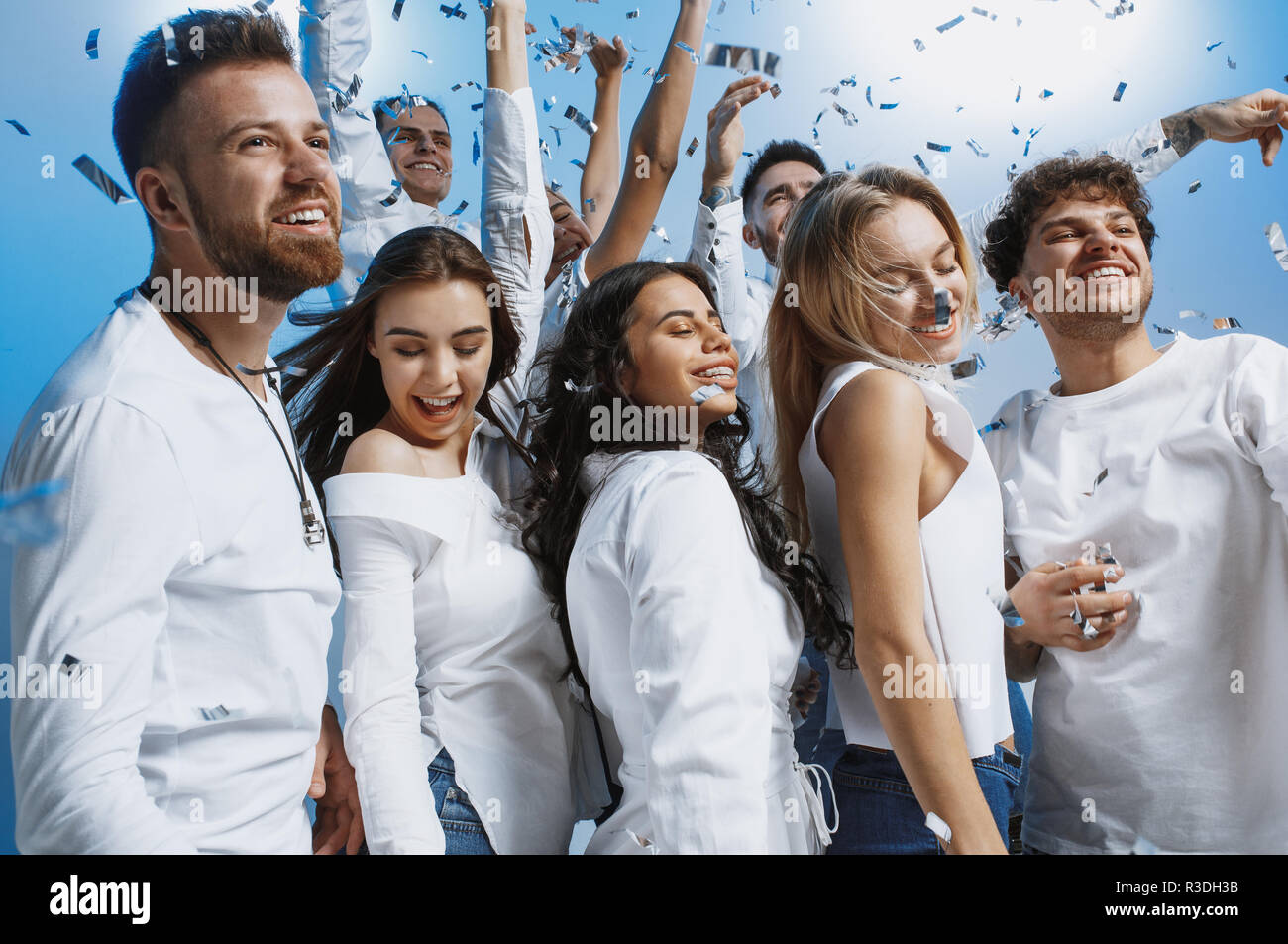 Group of cheerful joyful young people standing and celebrating together ...