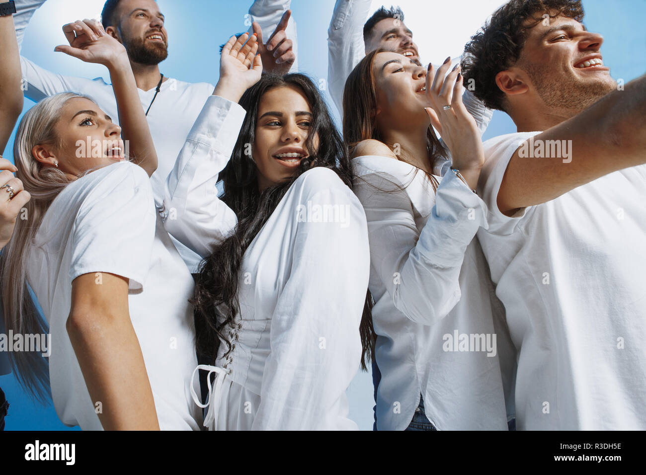 Group of cheerful joyful young people standing and celebrating together ...