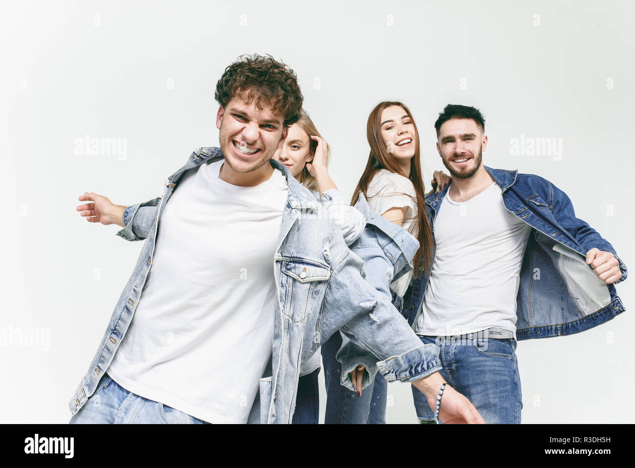 Group of smiling friends in fashionable jeans. The young men and woman ...