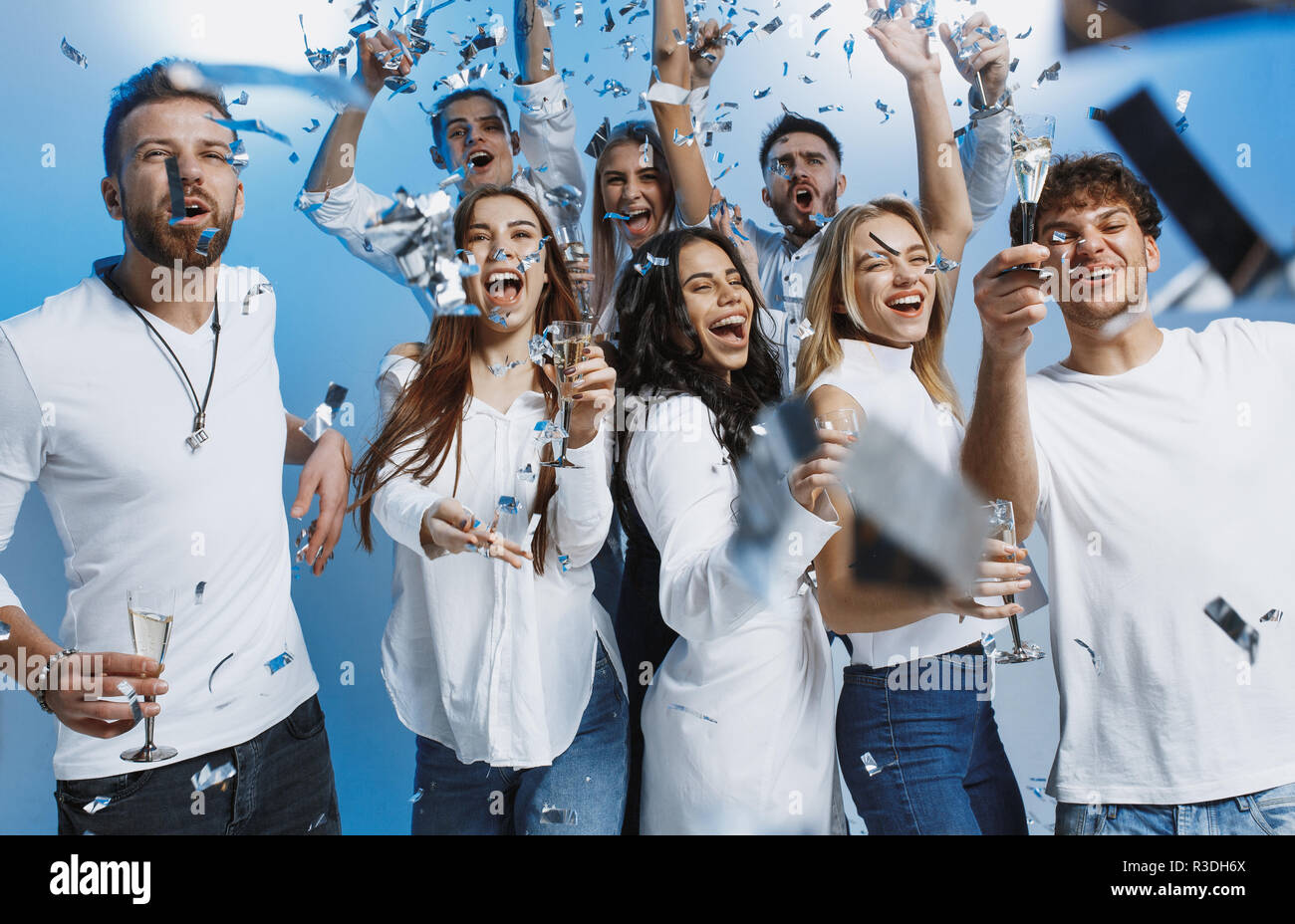 Group of cheerful joyful young people standing and celebrating together ...