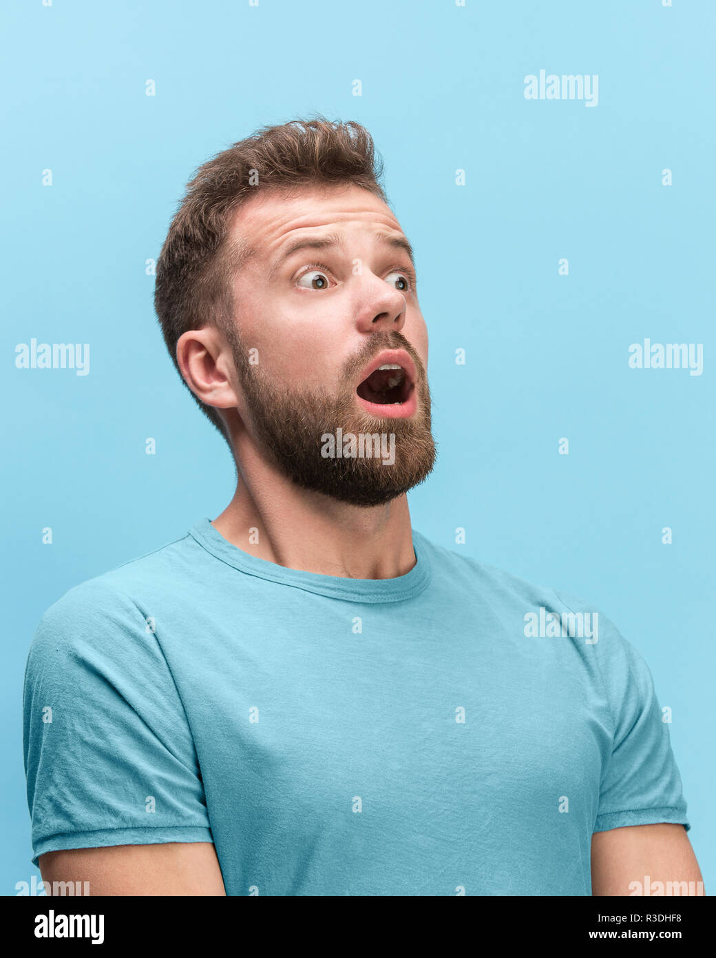 The surprised and astonished young man screaming with open mouth ...