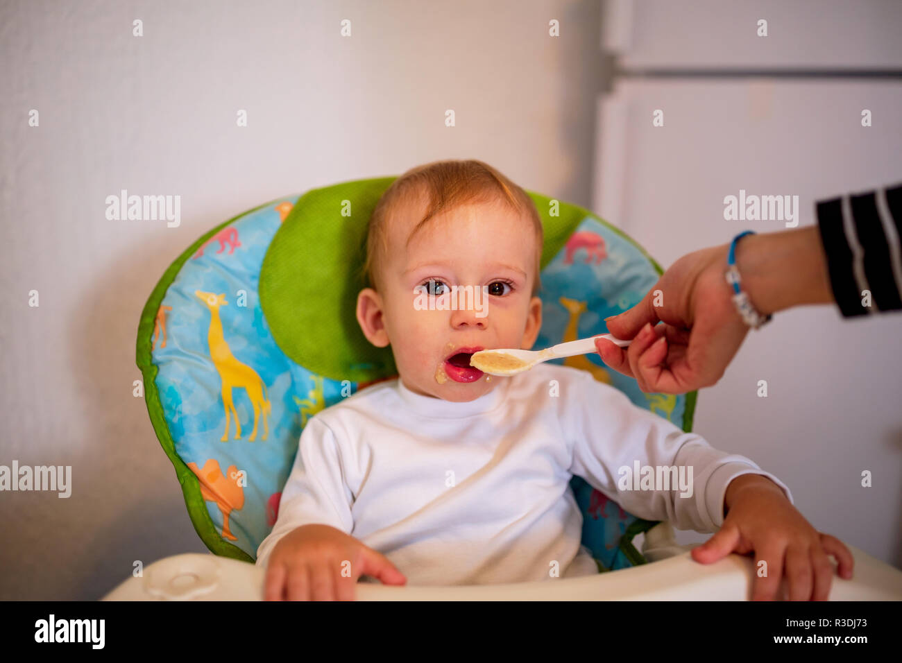 Adorable hungry baby child likes to eat in the kitchen Stock Photo - Alamy