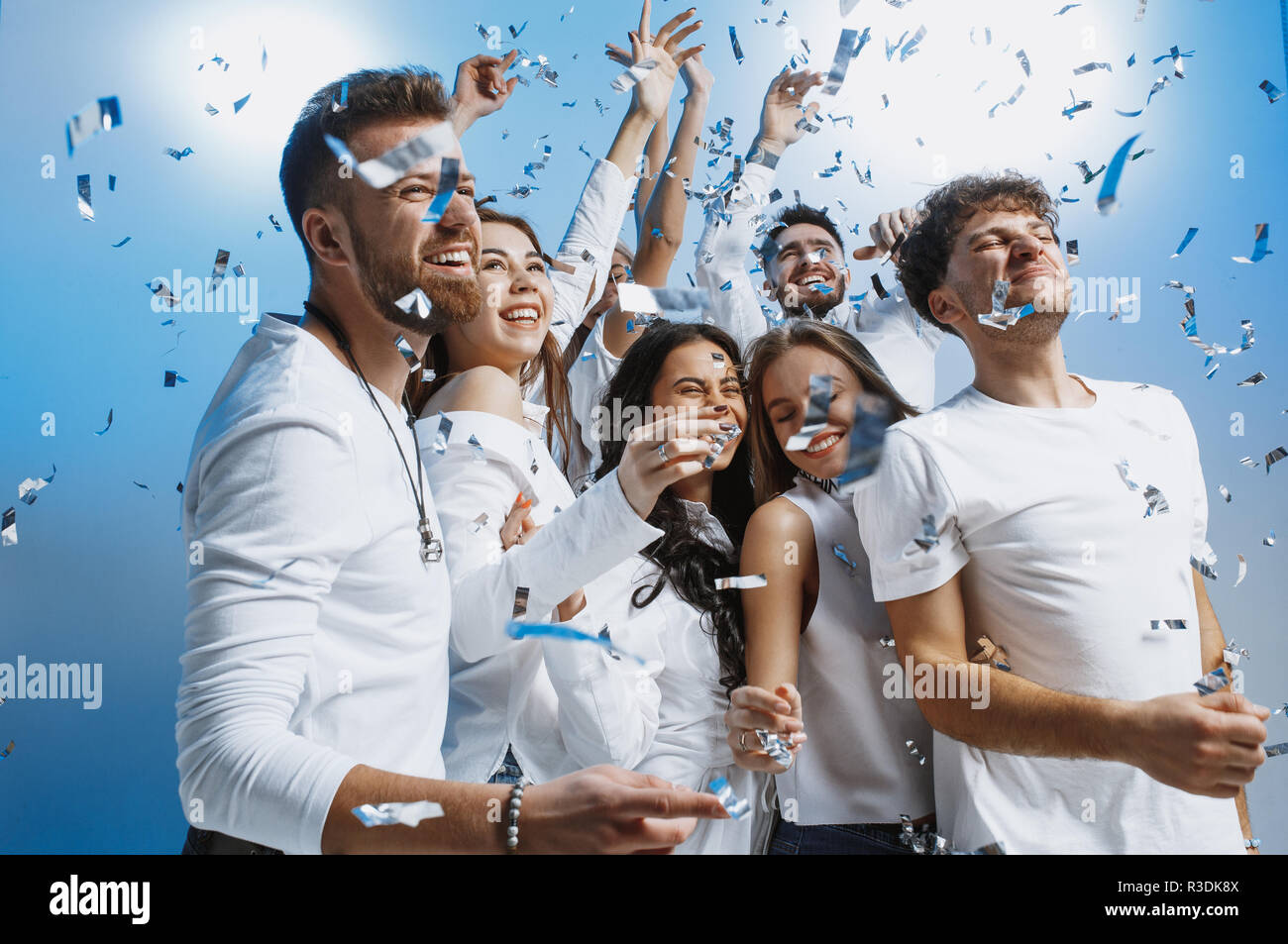 Group of cheerful joyful young people standing and celebrating together ...