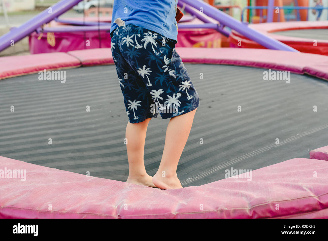 Boy jumping on a trampoline helped by ropes at a fair Stock Photo - Alamy