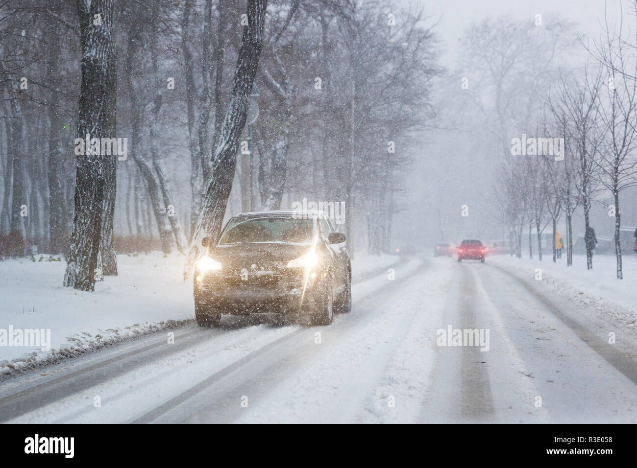 Cars moving on slippery snowy road at city street during heavy snowfall ...