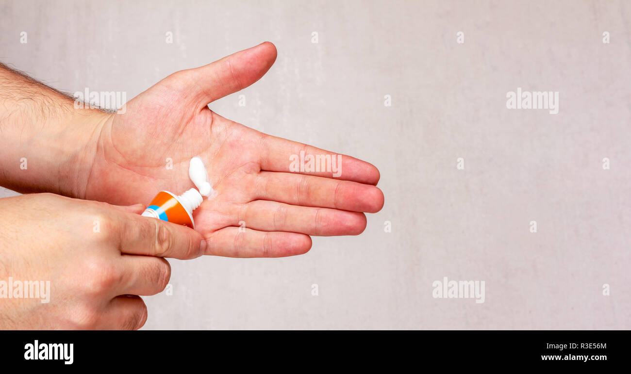 Man applying hand cream on grey background with copy space, closeup ...