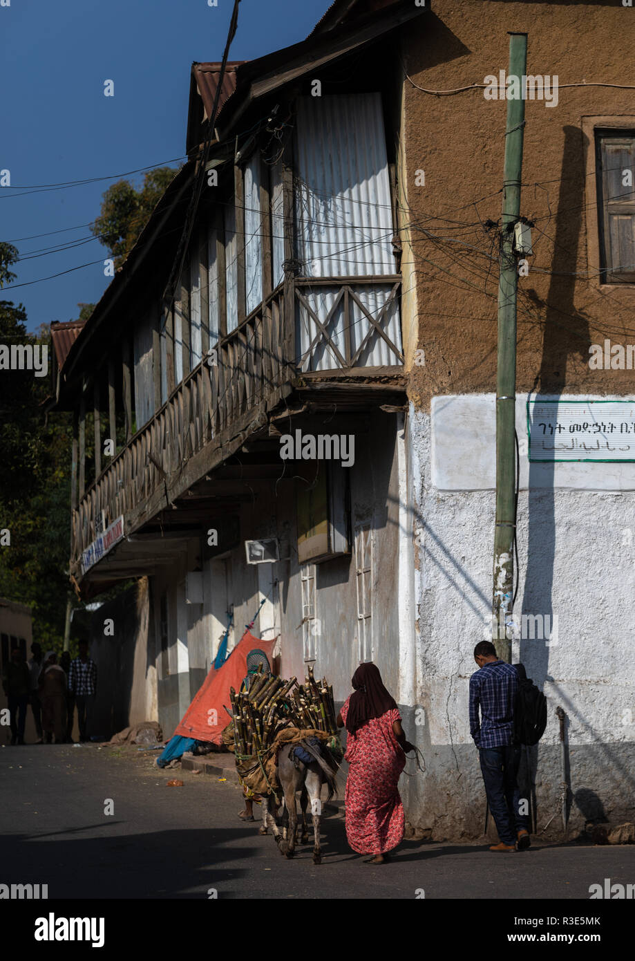 Harari people passing in front of an old house with a wooden balcony ...