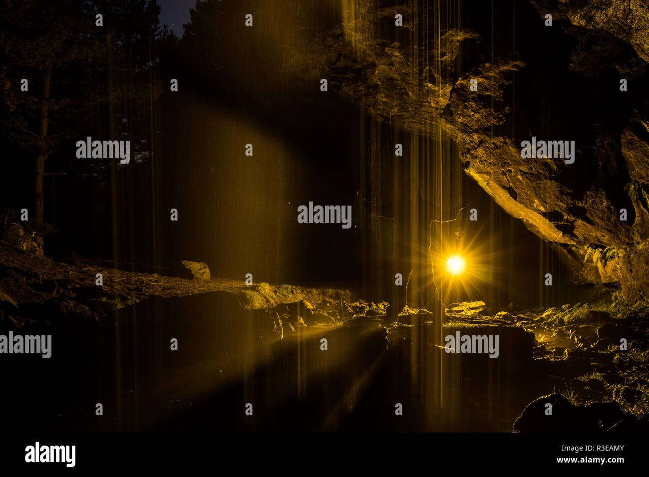 Night photograph inside a cave with waterfall and illuminated with ...