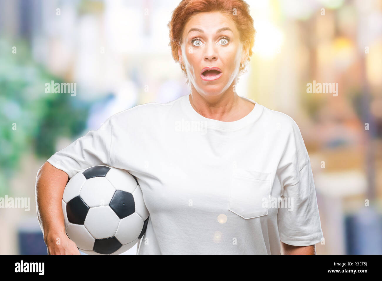 Atrractive senior caucasian redhead woman holding soccer ball over ...