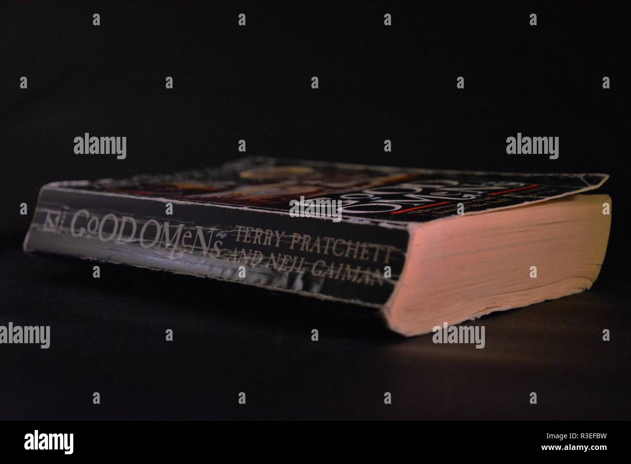 dog eared well worn paperback book , good omens, on dark background ...