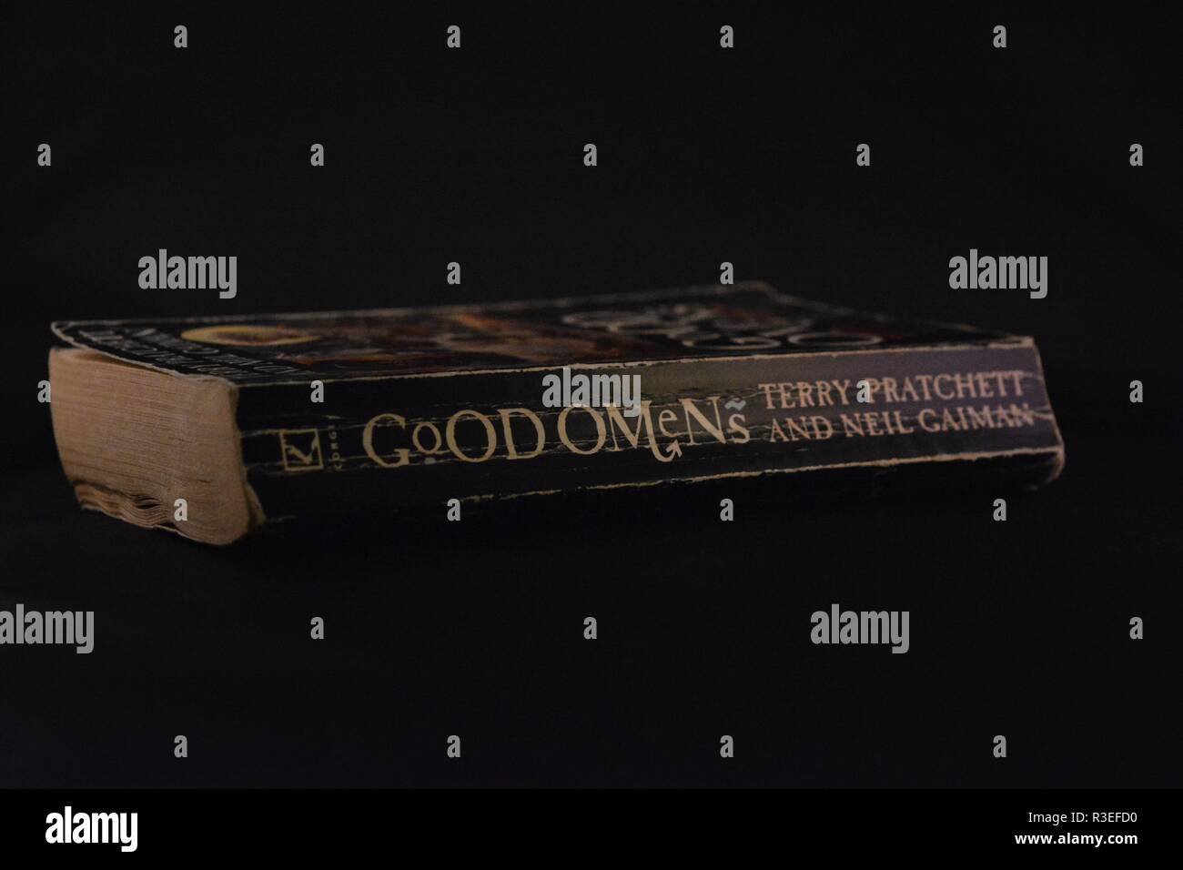 dog eared well worn paperback book , good omens, on dark background ...