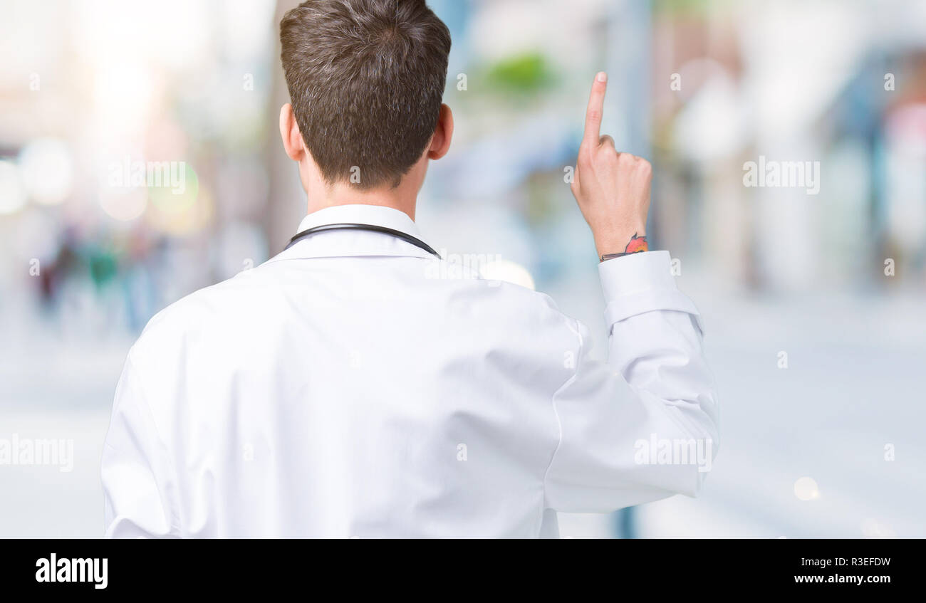 Young doctor man wearing hospital coat over isolated background Posing ...