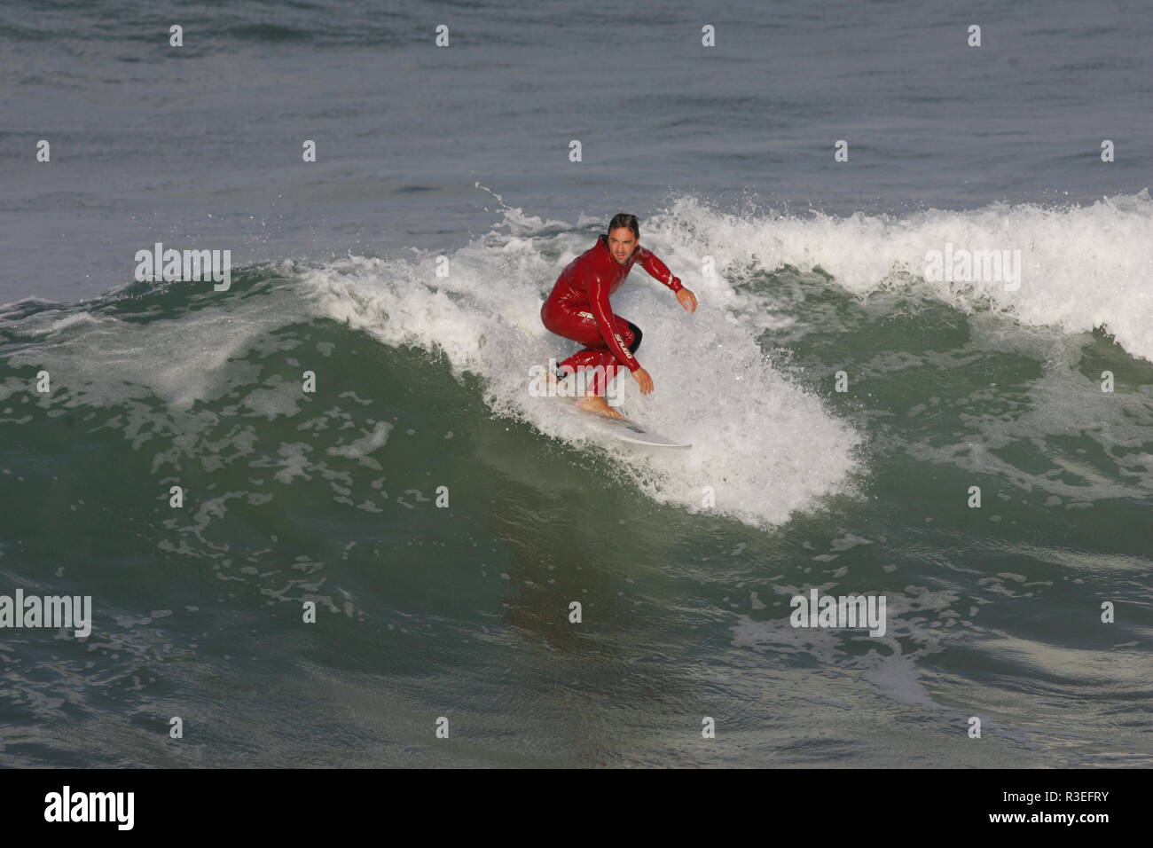 Green water red wetsuit surfer hi-res stock photography and images - Alamy