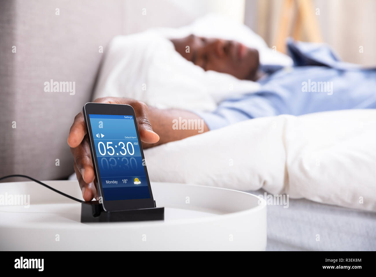 African Man Lying On Bed Snoozing Alarm On Mobile Phone Stock Photo - Alamy
