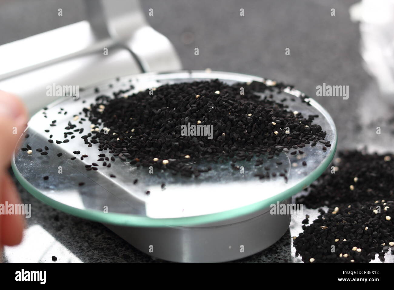 Weighing of black cumin seeds on kitchen scale Stock Photo - Alamy