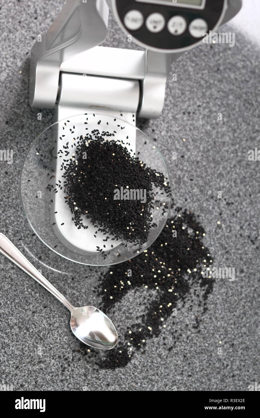 Weighing of black cumin seeds on kitchen scale Stock Photo - Alamy