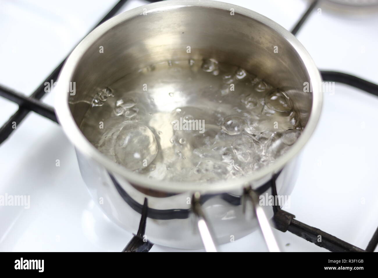 Boiling water in milk pan on gas stove Stock Photo - Alamy