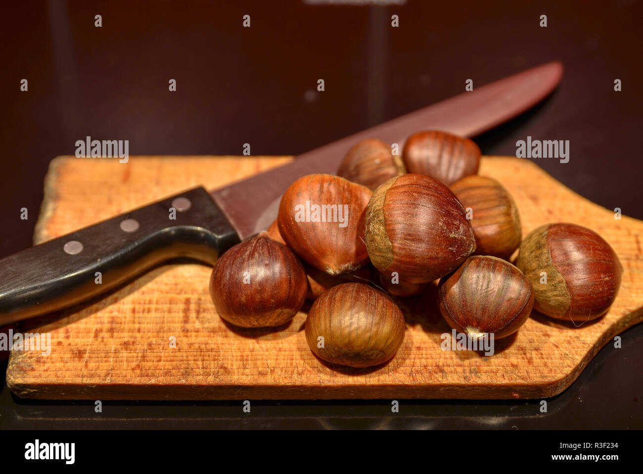 A wooden chopping board with a long, sharp-edged knife and a group of ...