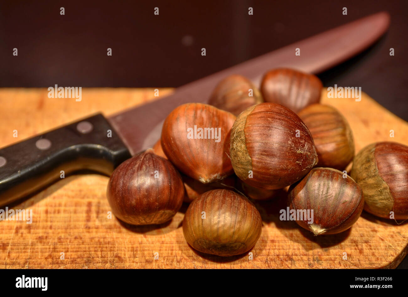 A wooden chopping board with a long, sharp-edged knife and a group of ...