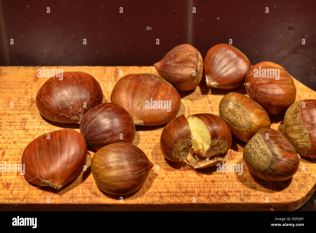 A wooden chopping board with a group of chestnuts looking full and rich ...