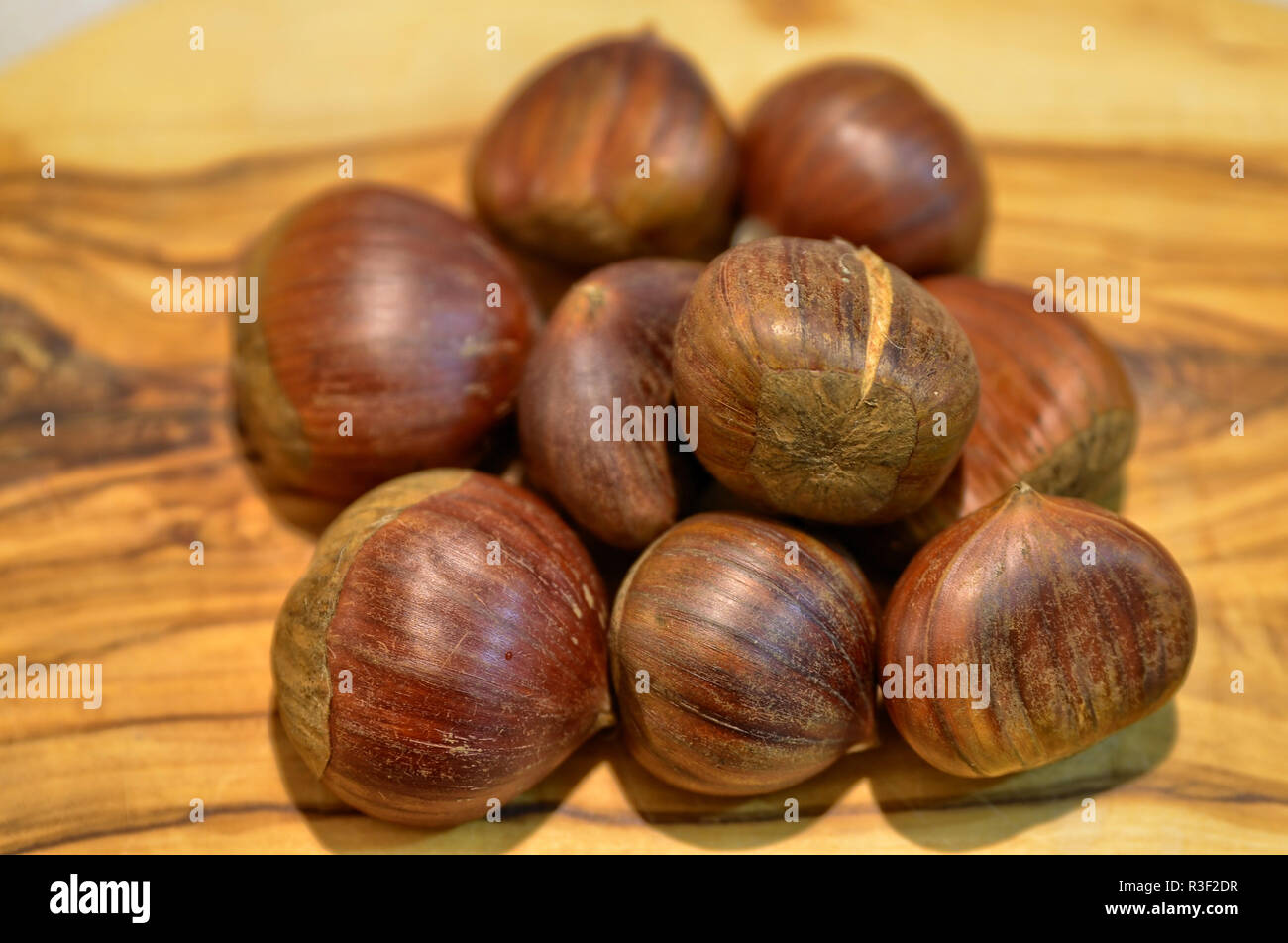 A wooden chopping board with a group of chestnuts looking full and rich ...