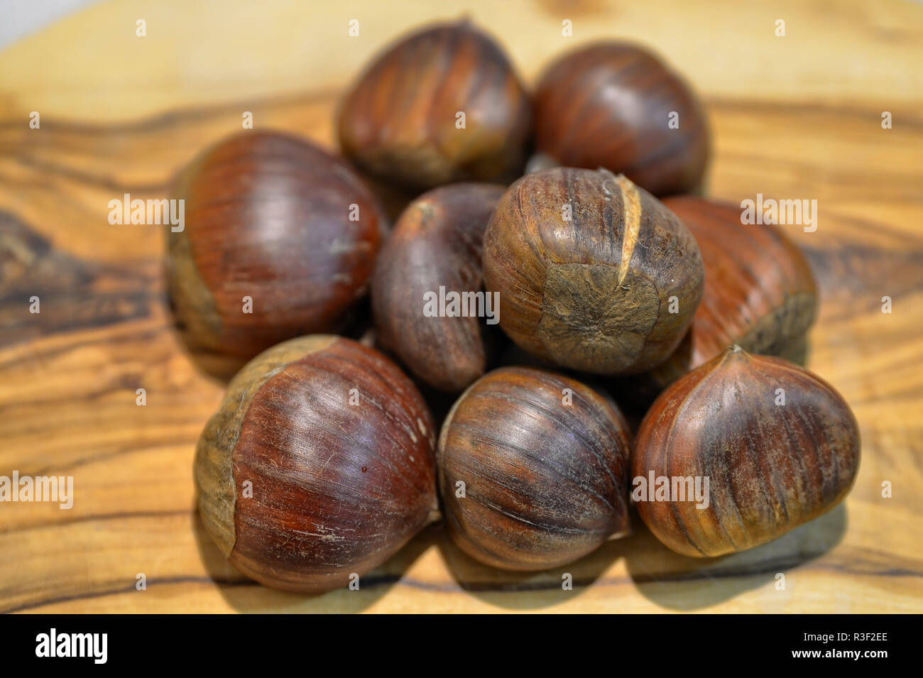 A wooden chopping board with a group of chestnuts looking full and rich ...