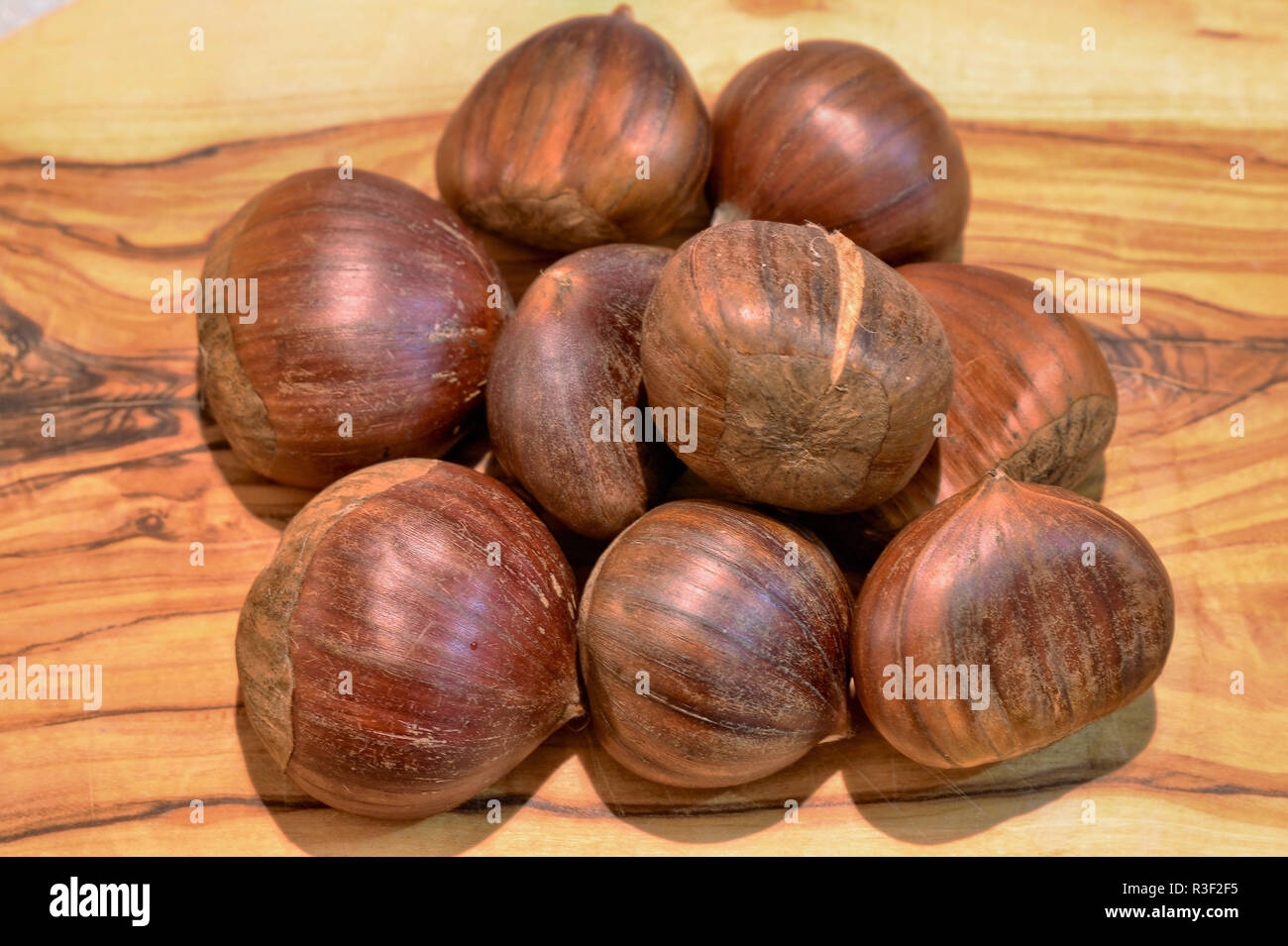 A wooden chopping board with a group of chestnuts looking full and rich ...