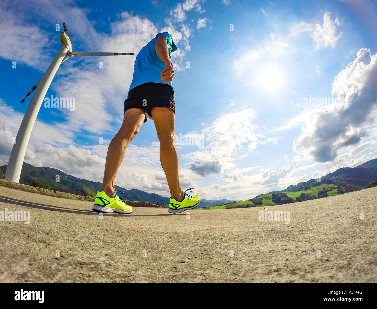 Male athlete runner walking in mountains at wind turbine background ...