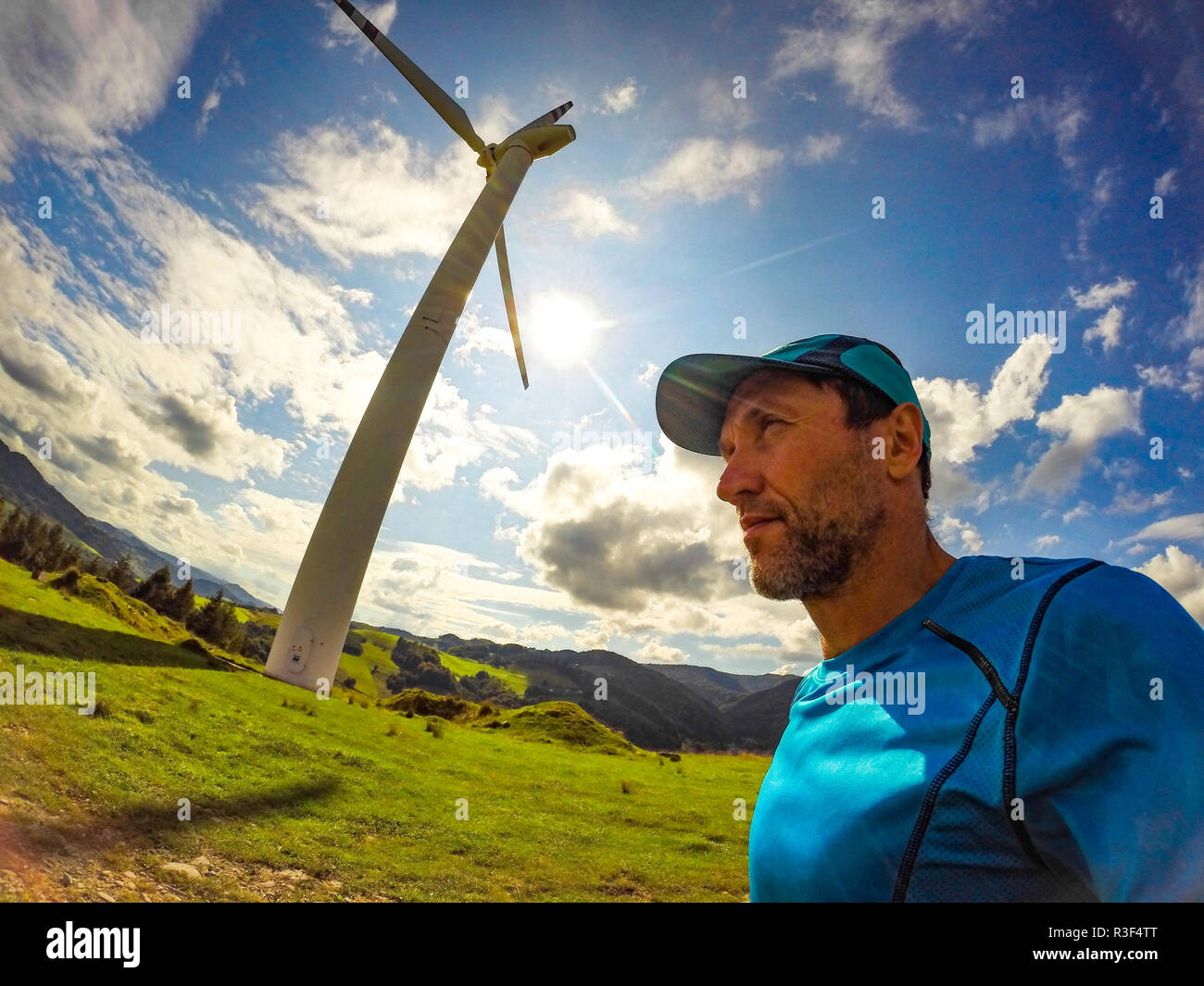 Male athlete running in mountains at wind turbine background Stock ...