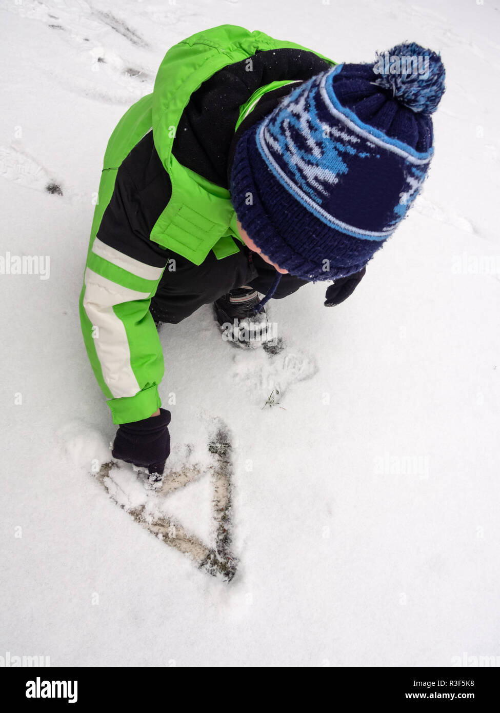Boy writing letter A in snow Stock Photo - Alamy