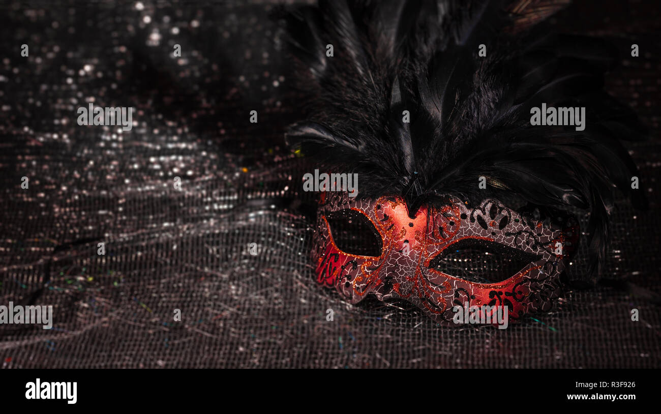 Carnival time. Venetian mask, red with feathers, on black shiny ...