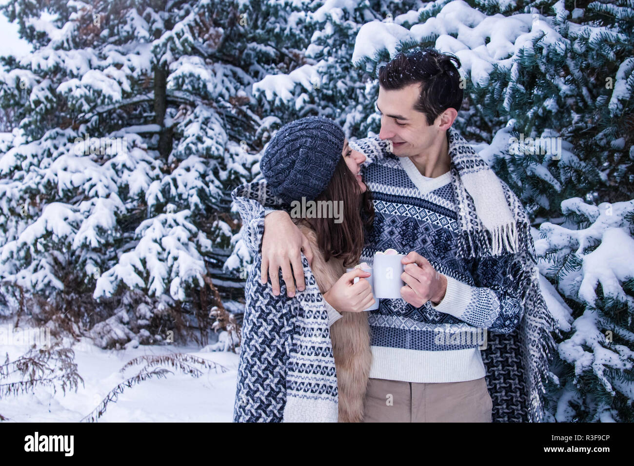 Couple hugs and drinks coffee with marshmallow in winter forest Stock ...