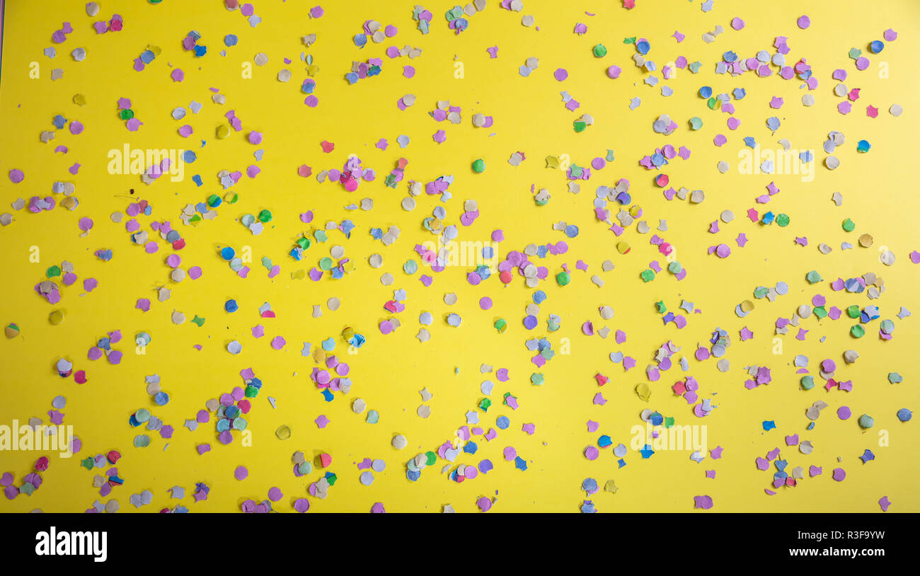 Carnival or birthday party. Colorful confetti on bright yellow ...