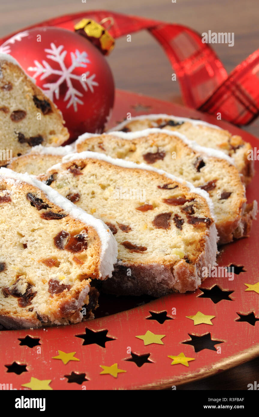 Christmas Stollen fruit cake with powdered sugar on table with red ...