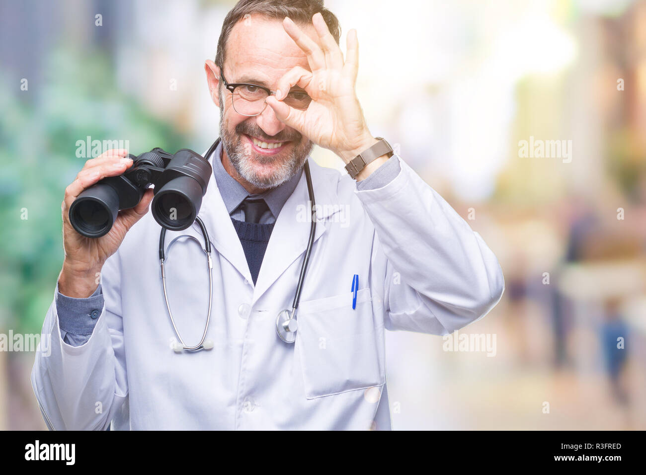 Middle age senior hoary doctor man looking through binoculars isolated ...
