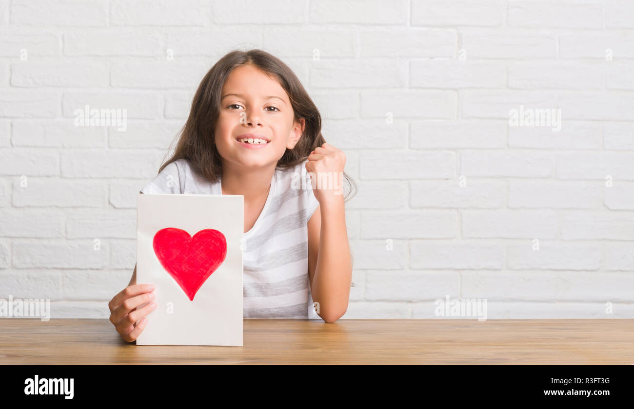 Young hispanic kid sitting on the table giving mother day card ...