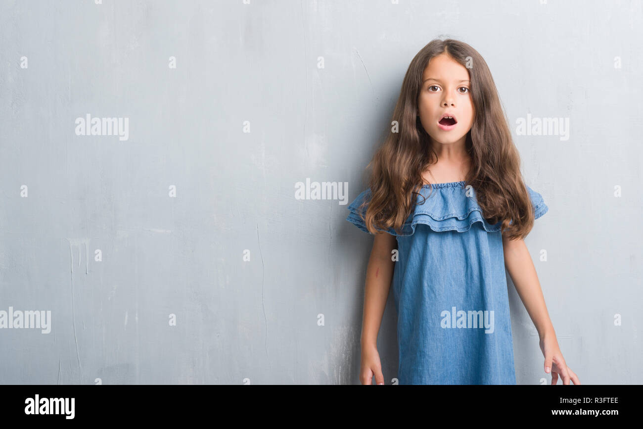 Young hispanic kid over grunge grey wall afraid and shocked with ...