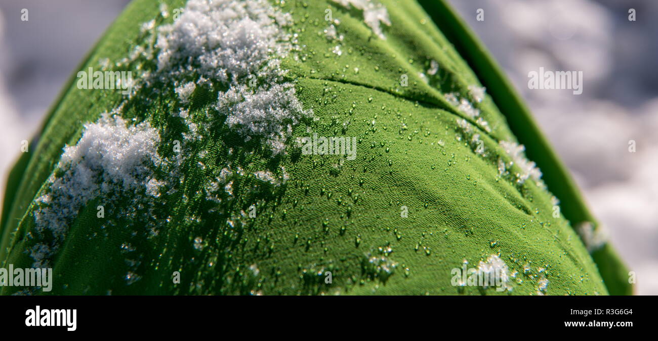 Snow and water droplets on green waterproof fabric from skiing clothes ...