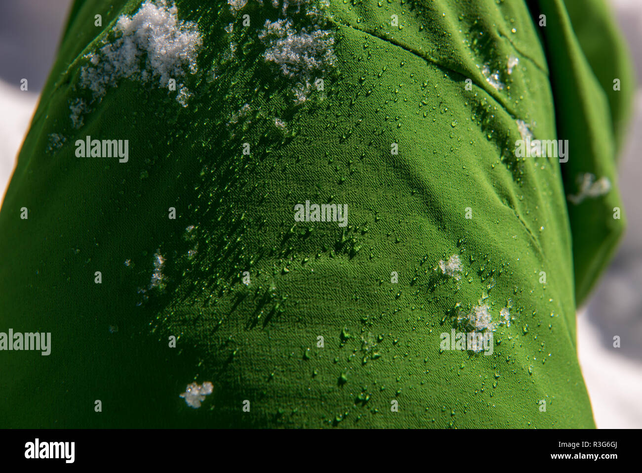 Snow and water droplets on green waterproof fabric from skiing clothes ...