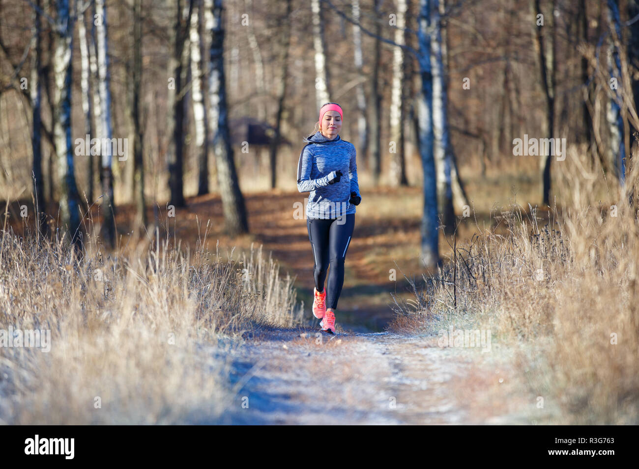 Young slim girl running in the park in early winter. Attractive woman ...