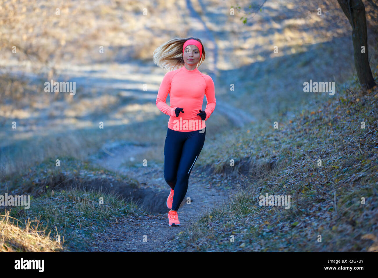 Young slim girl running in the park in early winter. Attractive woman ...