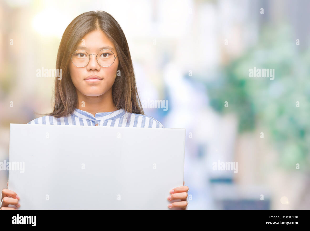 Young asian woman over isolated background holding blank banner with a ...
