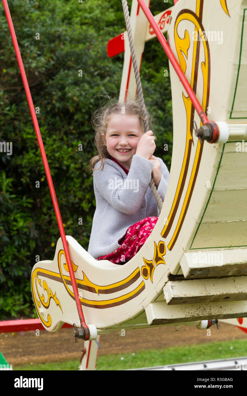 Girl age 6 years in a swinging gondola carriage on a traditional self ...