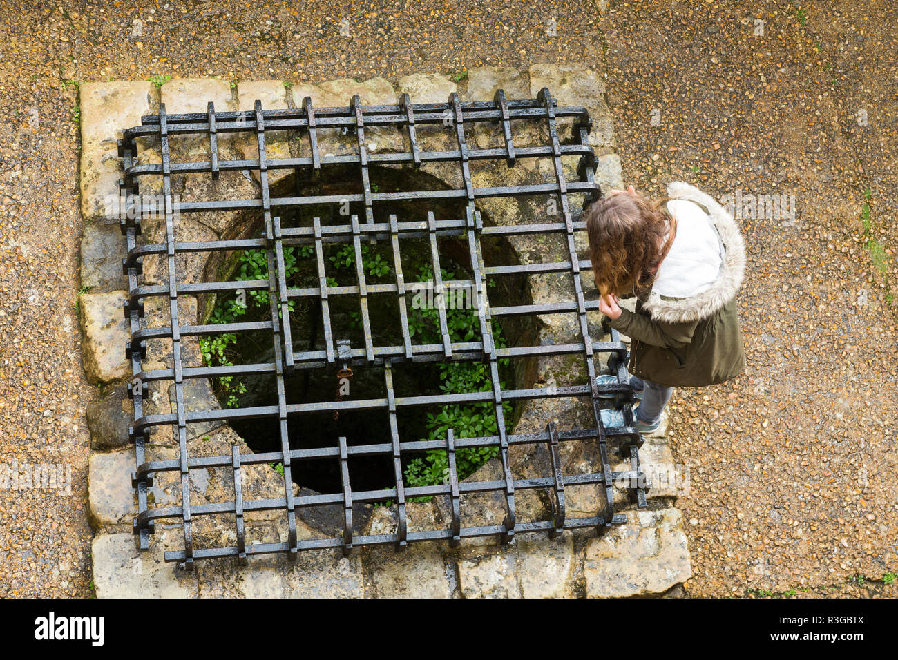 Tourist / visitor peers down into covered hole (presumably a water well ...