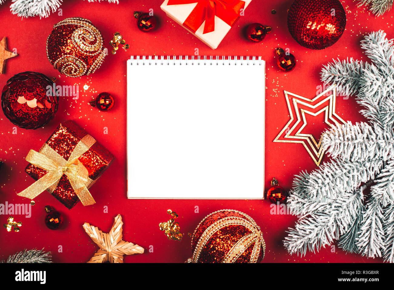 White square notebook and glittering Christmas decorations on red ...