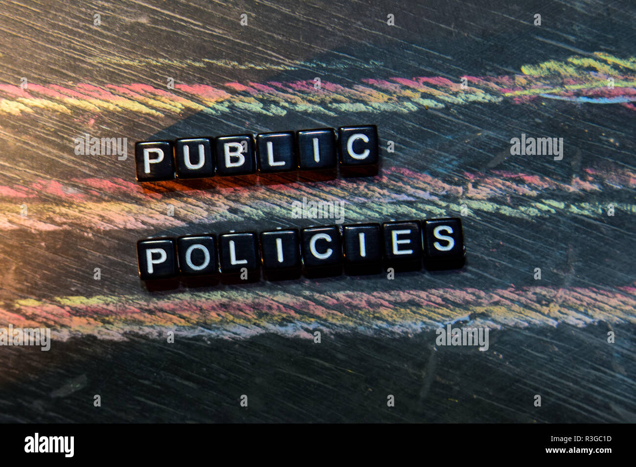 Public Policies on wooden blocks. Cross processed image with blackboard ...