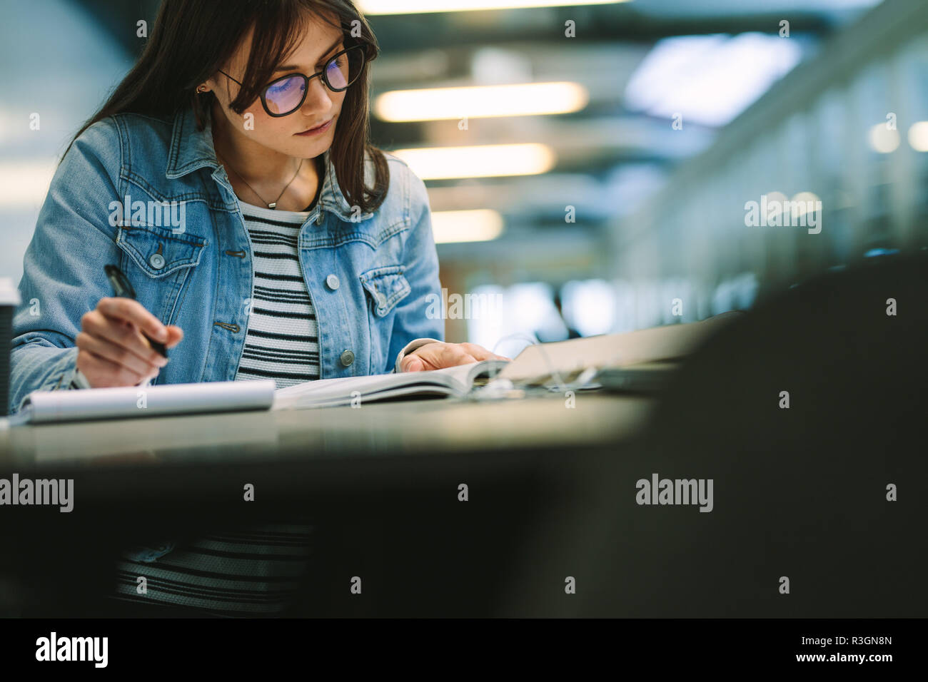 university student studying at college library. Female student reading ...