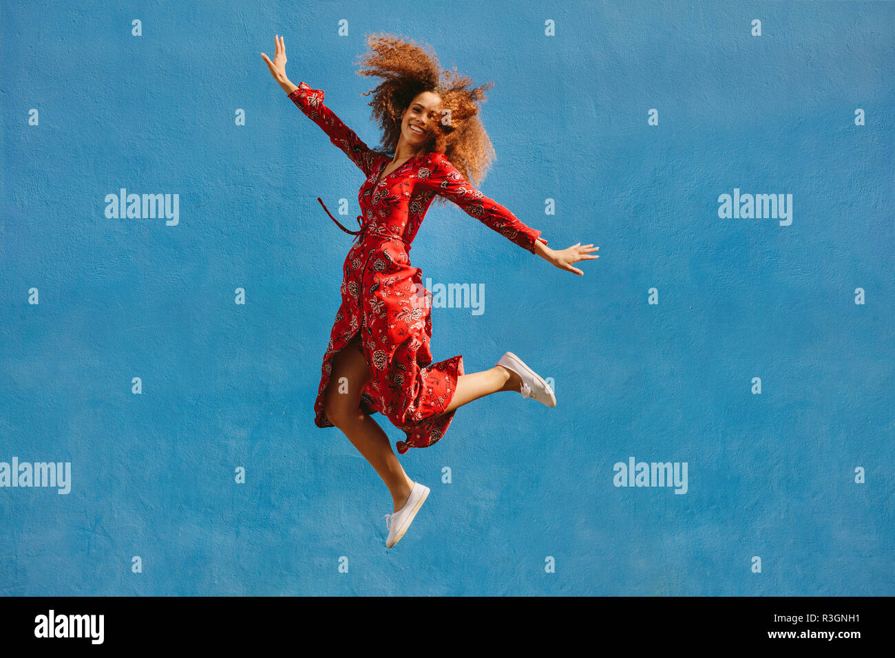 Young female model in red sundress jumping with joy. Beautiful young ...