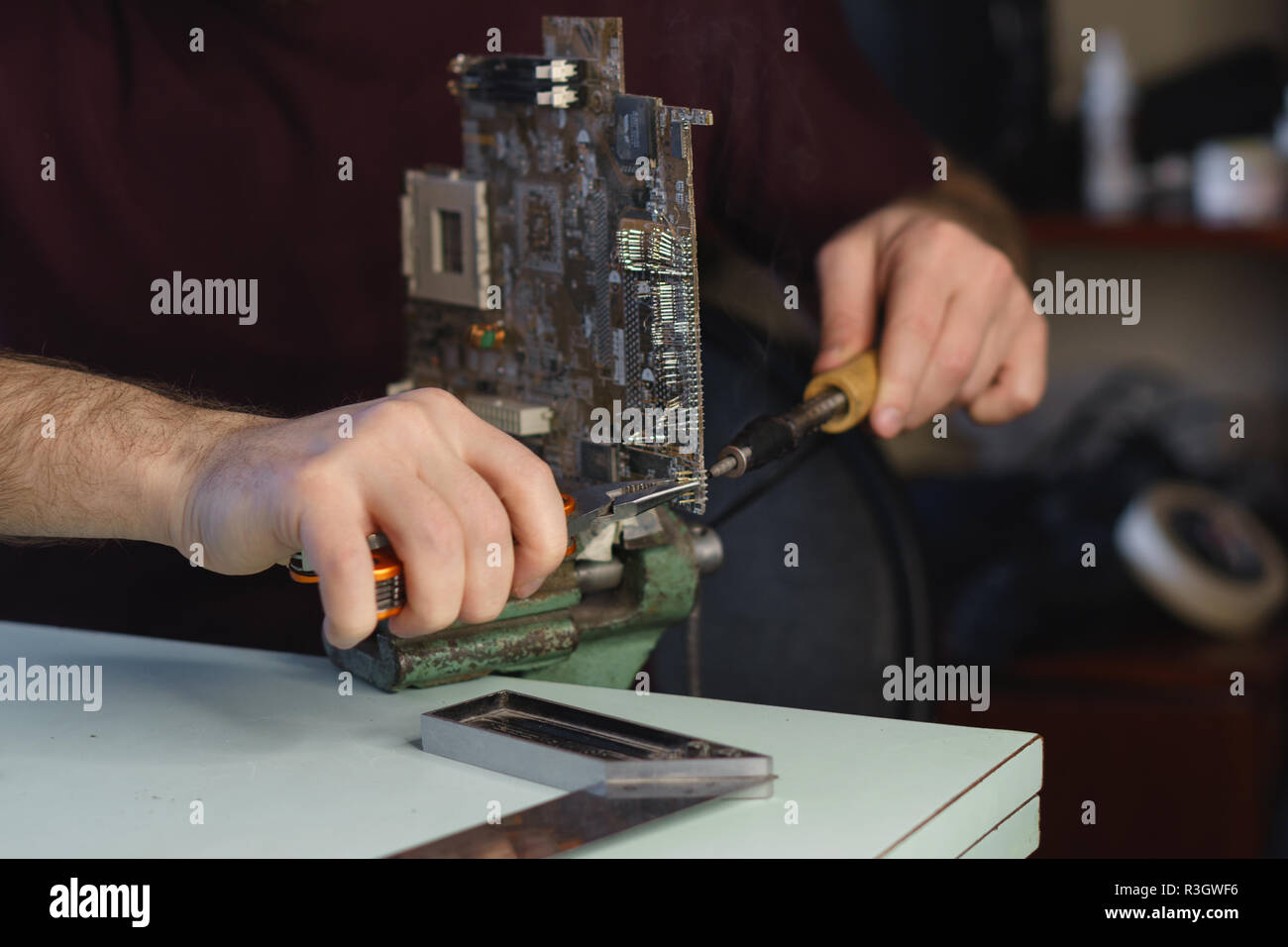 Repair motherboard. Service specialist solders. Microcircuit in a vice ...