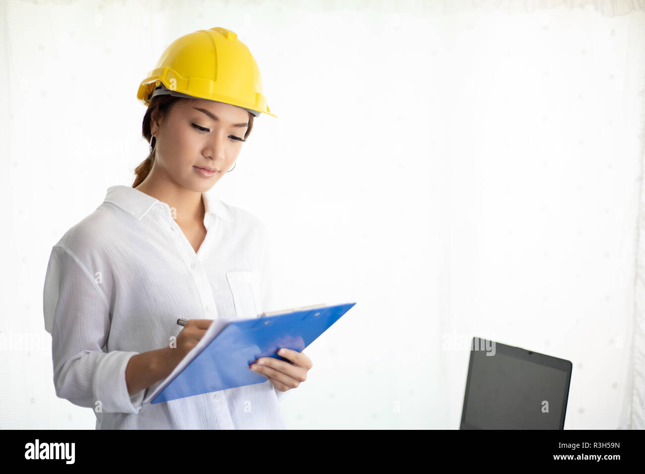 Asian women engineering inspecting and working and holding blueprints ...